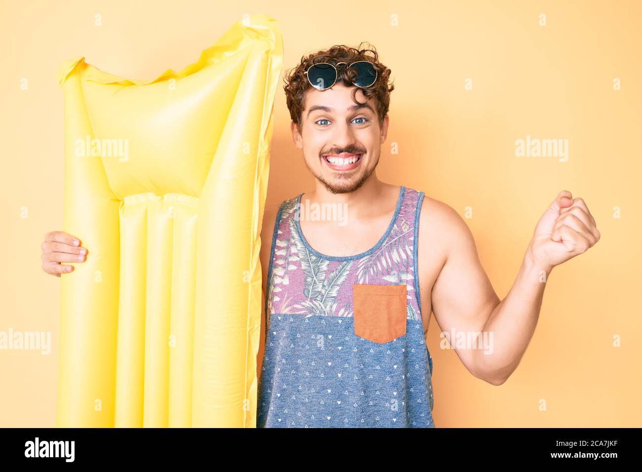Young caucasian man with curly hair wearing summer clothes and holding ...