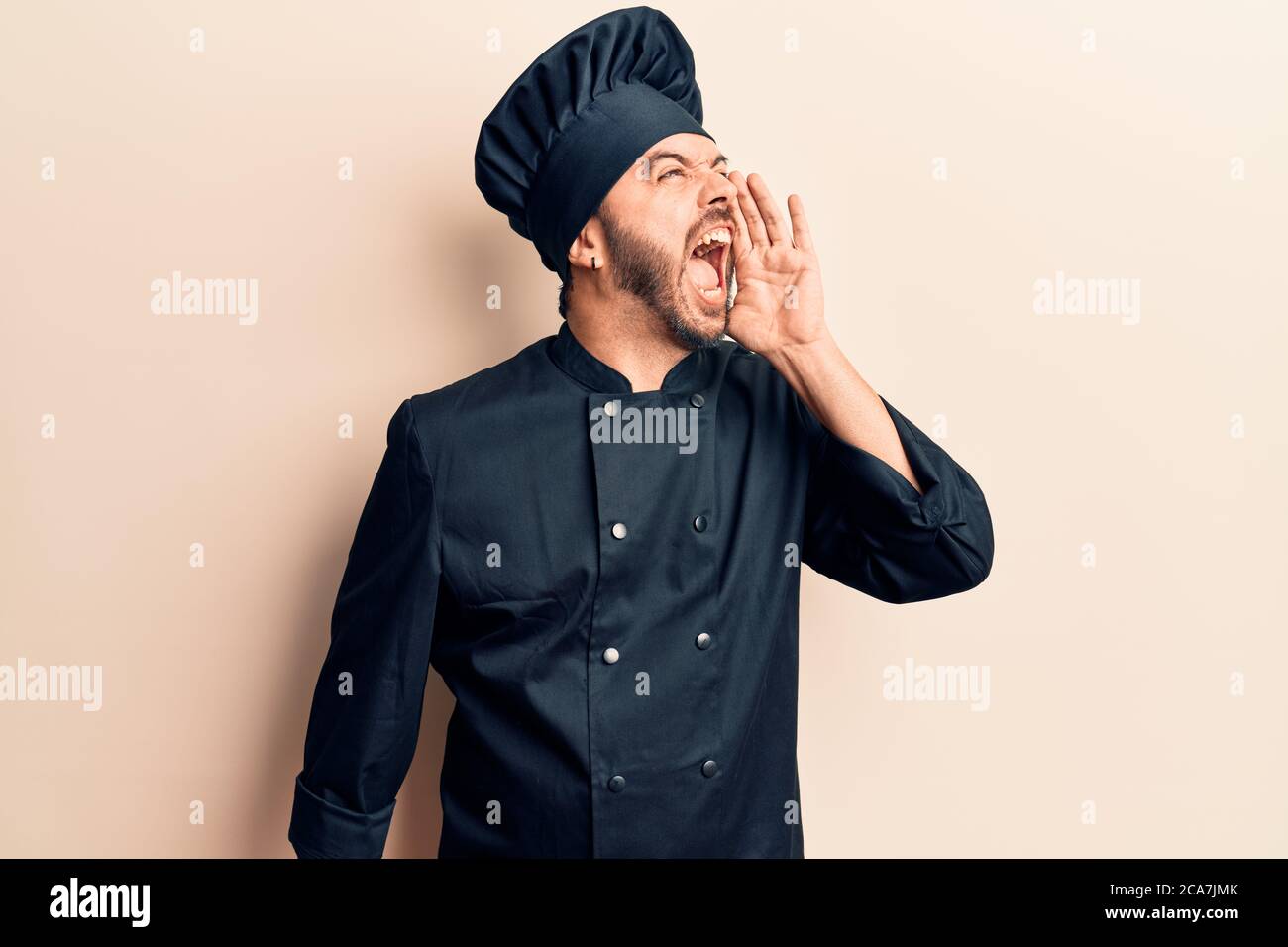 Young hispanic man wearing cooker uniform shouting and screaming loud ...