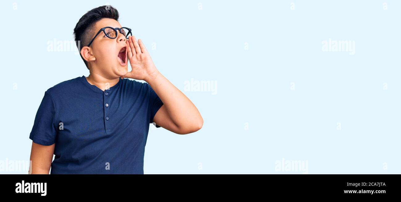 Little boy kid wearing casual clothes and glasses shouting and ...