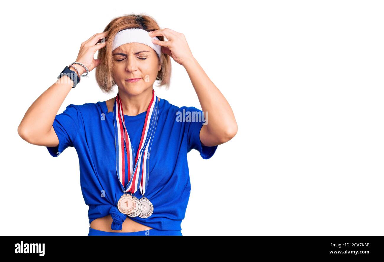 Young blonde woman wearing winner medals suffering from headache ...
