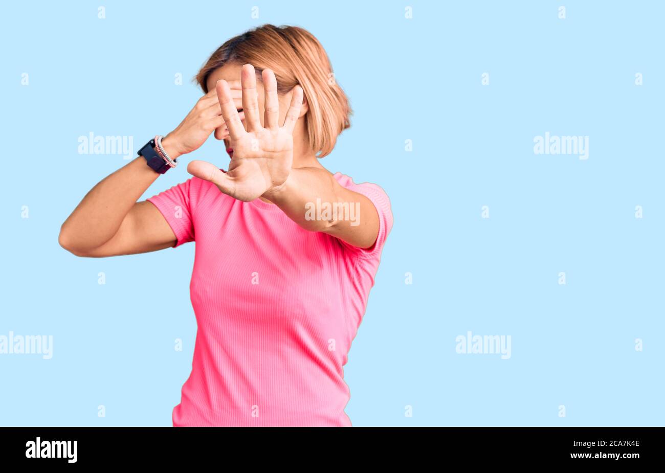 Young blonde woman wearing sportswear covering eyes with hands and ...
