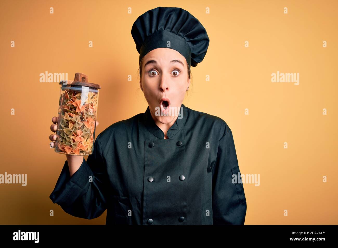 Young beautiful chef woman wearing cooker uniform and hat holding ...