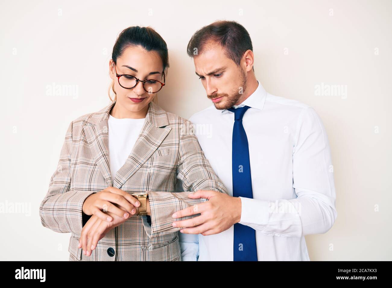 Beautiful couple wearing business clothes checking the time on wrist ...