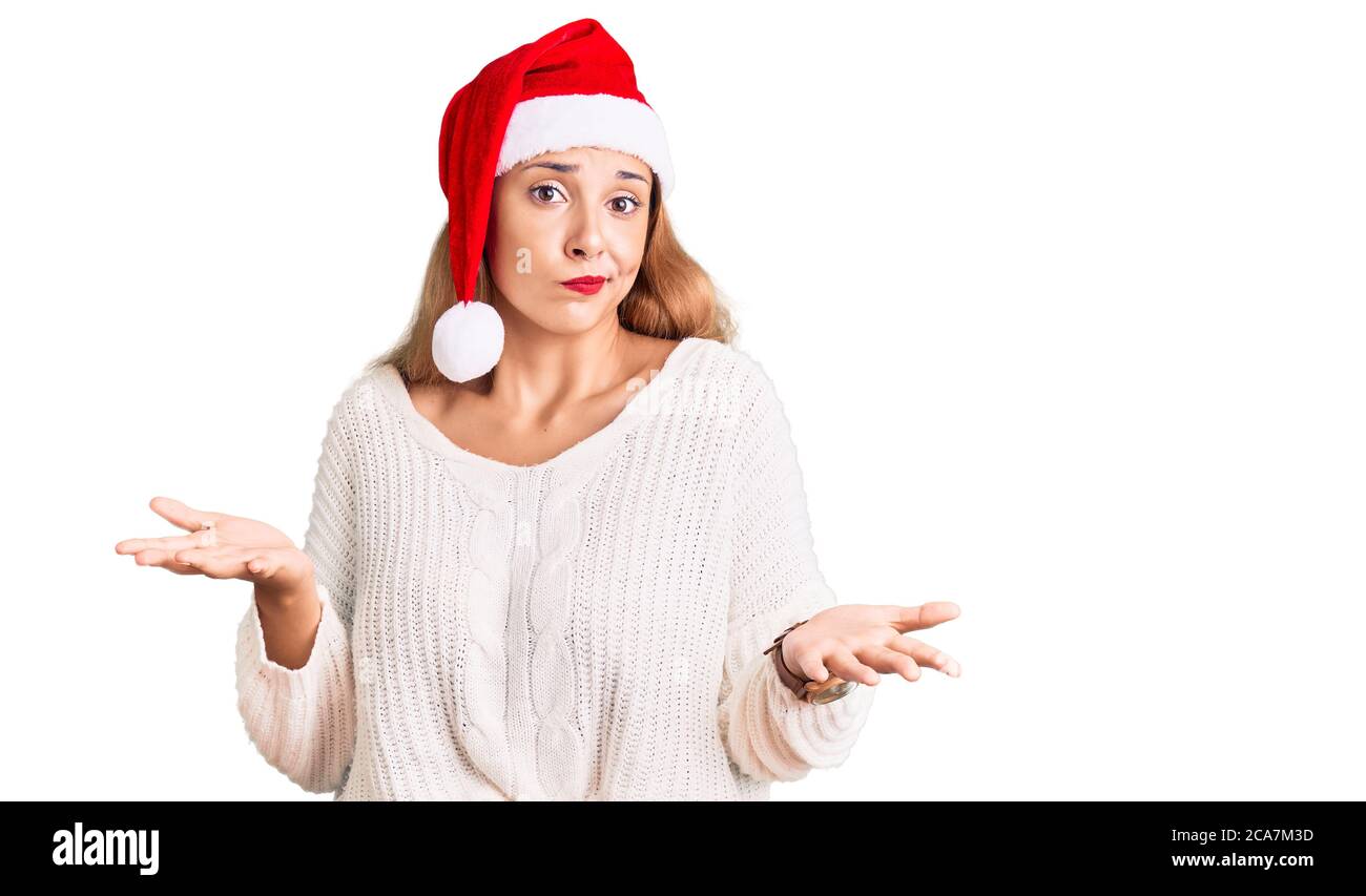 Beautiful young woman wearing christmas hat clueless and confused ...