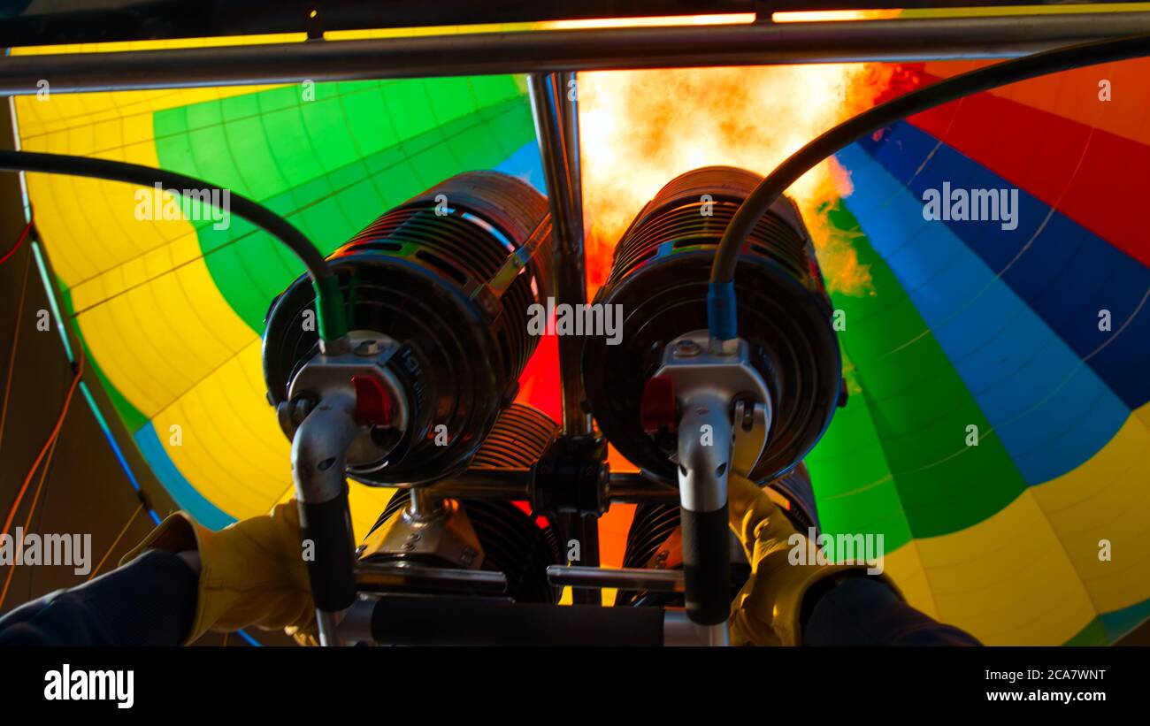 Flames in hot air balloon from burning propane as pilot fires up engine ...