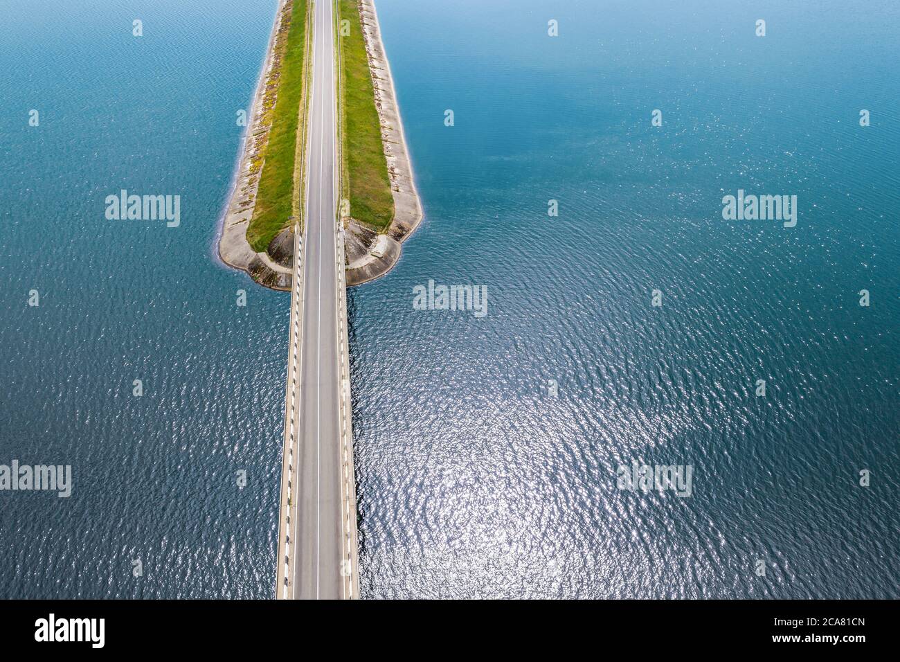 modern bridge with cars and straight asphalt road across blue lake. top ...