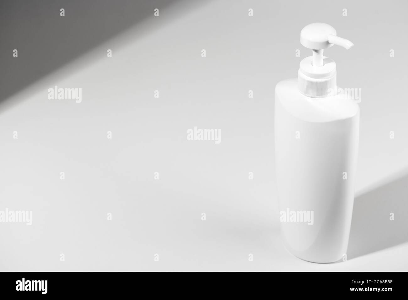 White unbranded bottle with dispenser on light shadow background. Blank ...