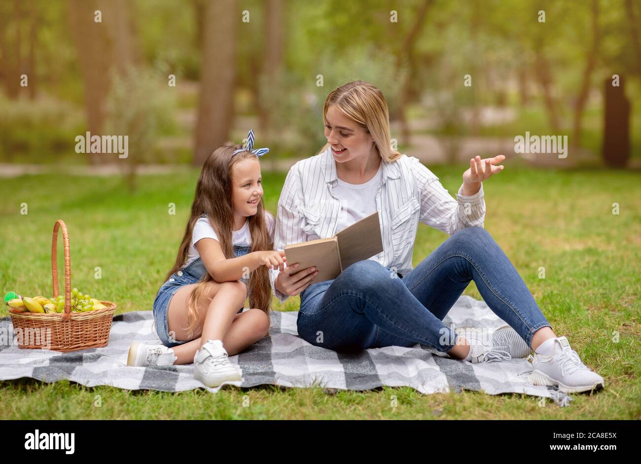 Positive Mother And Daughter Reading And Discussing Book In Park Stock ...