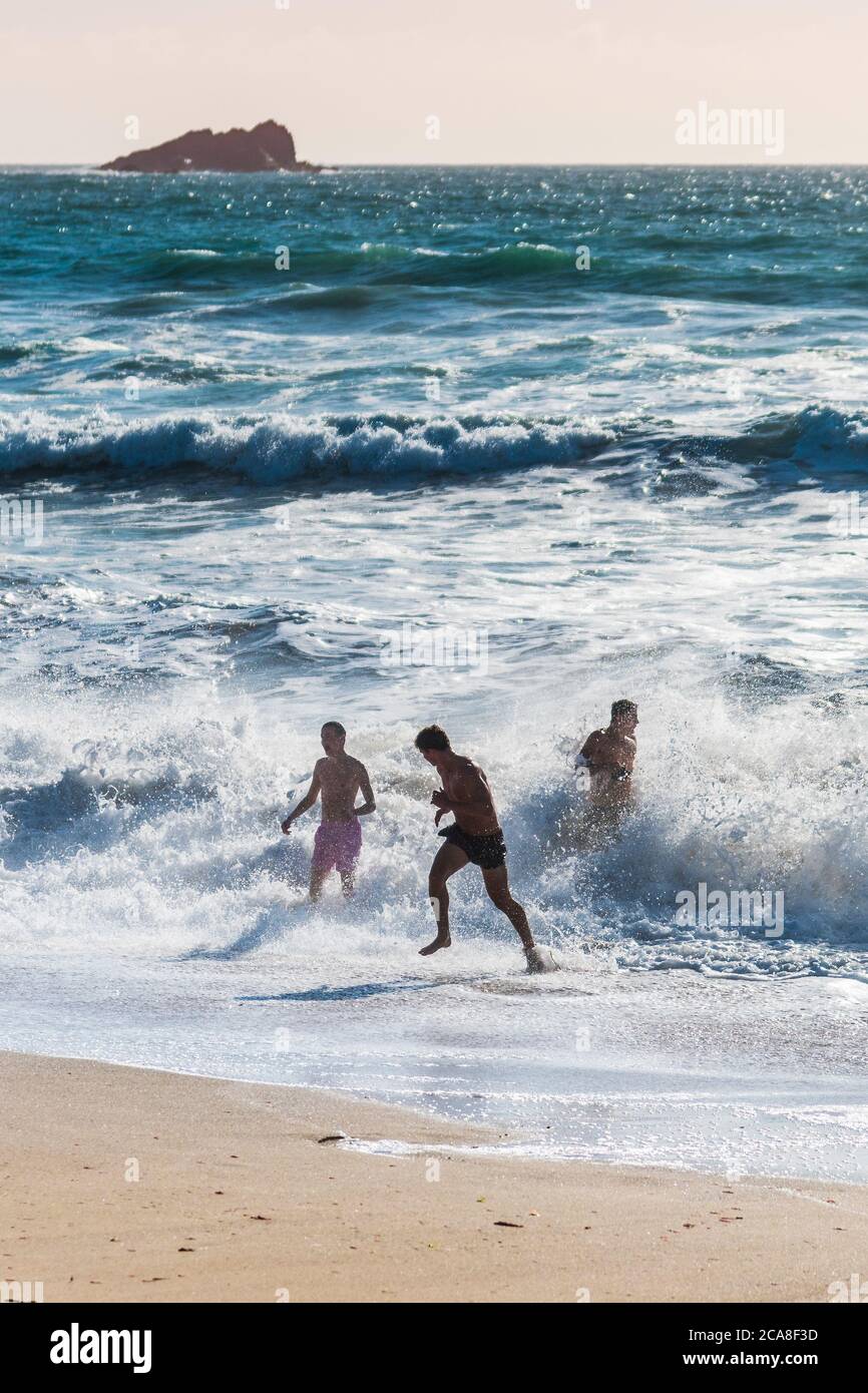 Male holidaymakers having fun in the sea at Fistral Beach in Newquay in ...