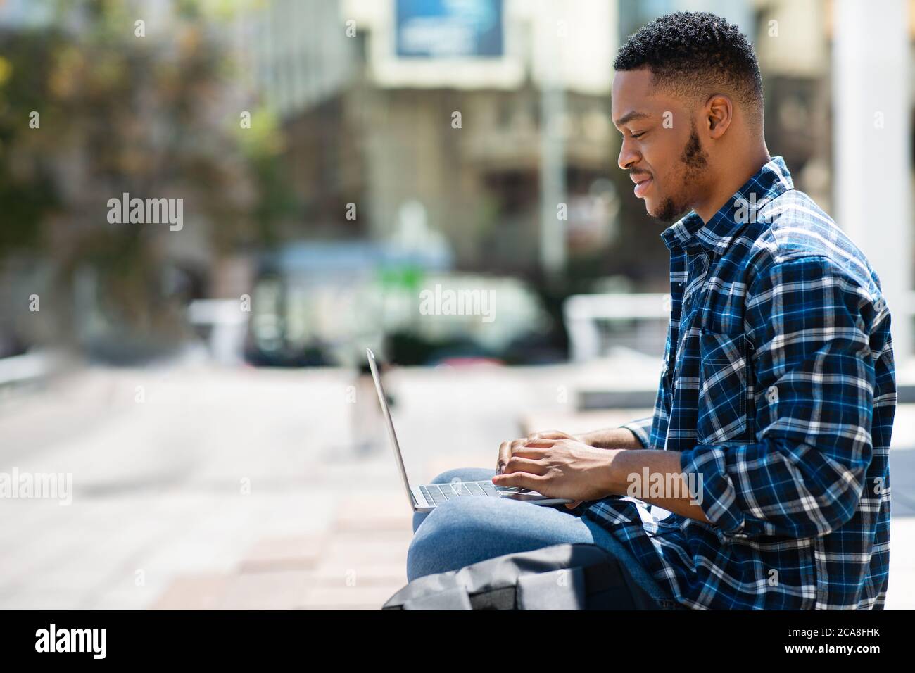 Black man using laptop, sitting in downtown with gadget Stock Photo - Alamy