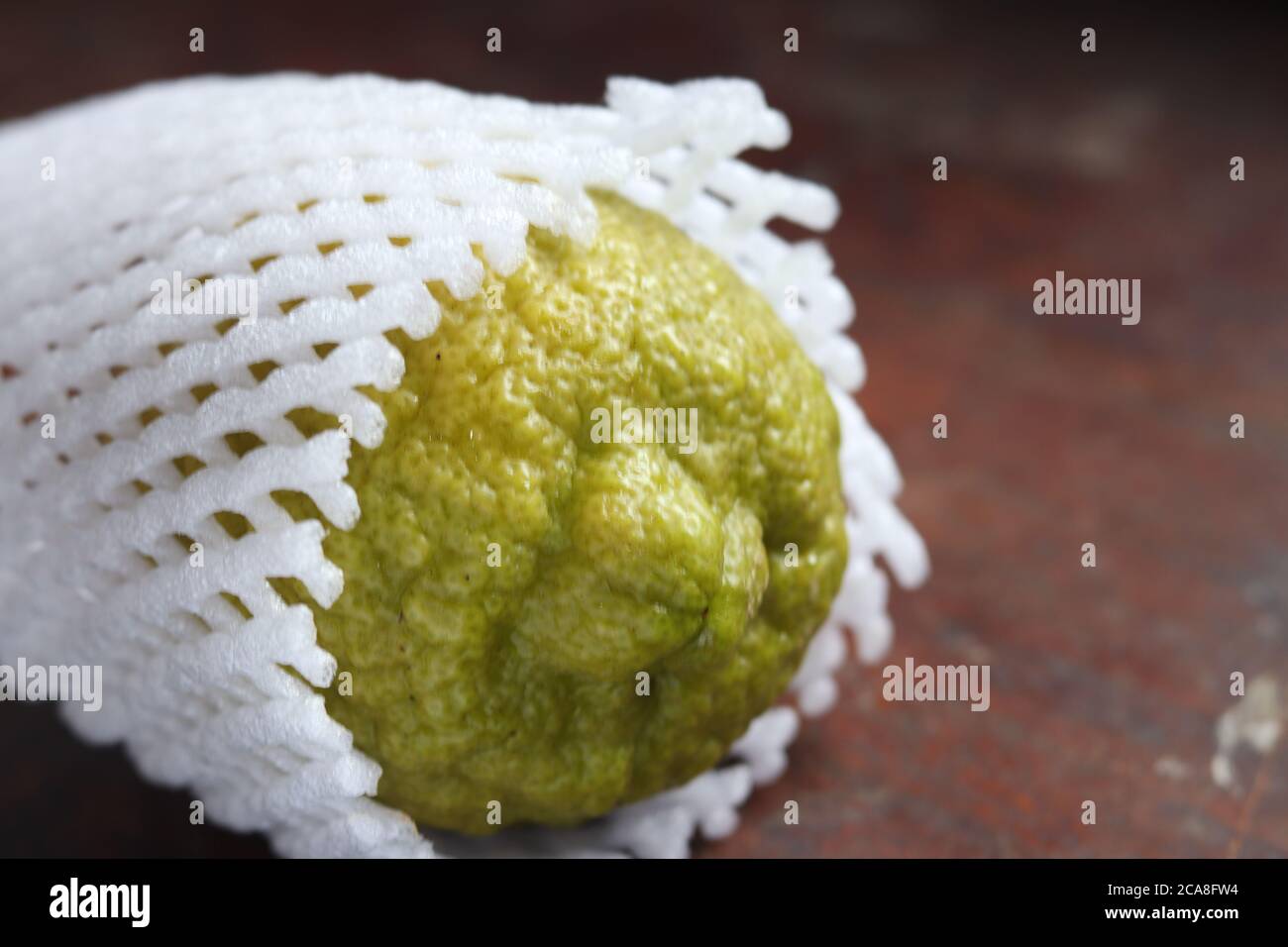yellow lemon wrapped in a white net with a wooden backdrop Stock Photo ...