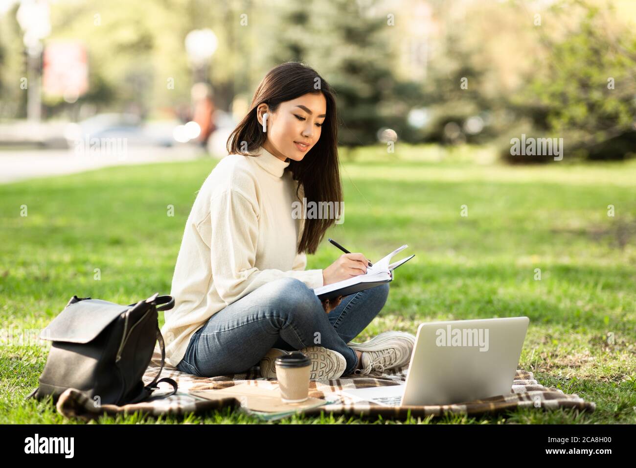 Girl writing in diary, sitting in parkland near university Stock Photo ...
