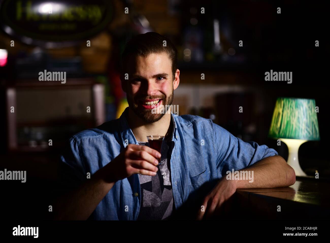 Man with beard sits in bar on blurred background. Friday night and ...