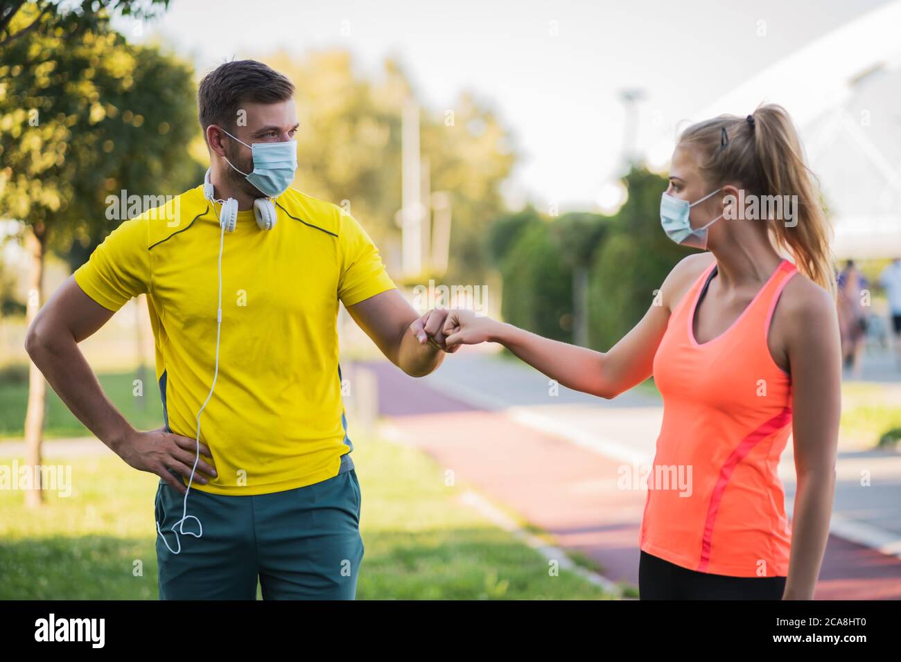 Young couple is getting ready for outdoor workout with protective masks ...