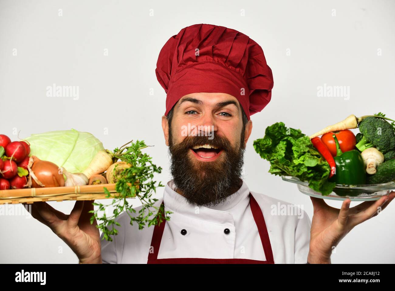 Young man chef holding lettuce and other vegetables smiling happily ...