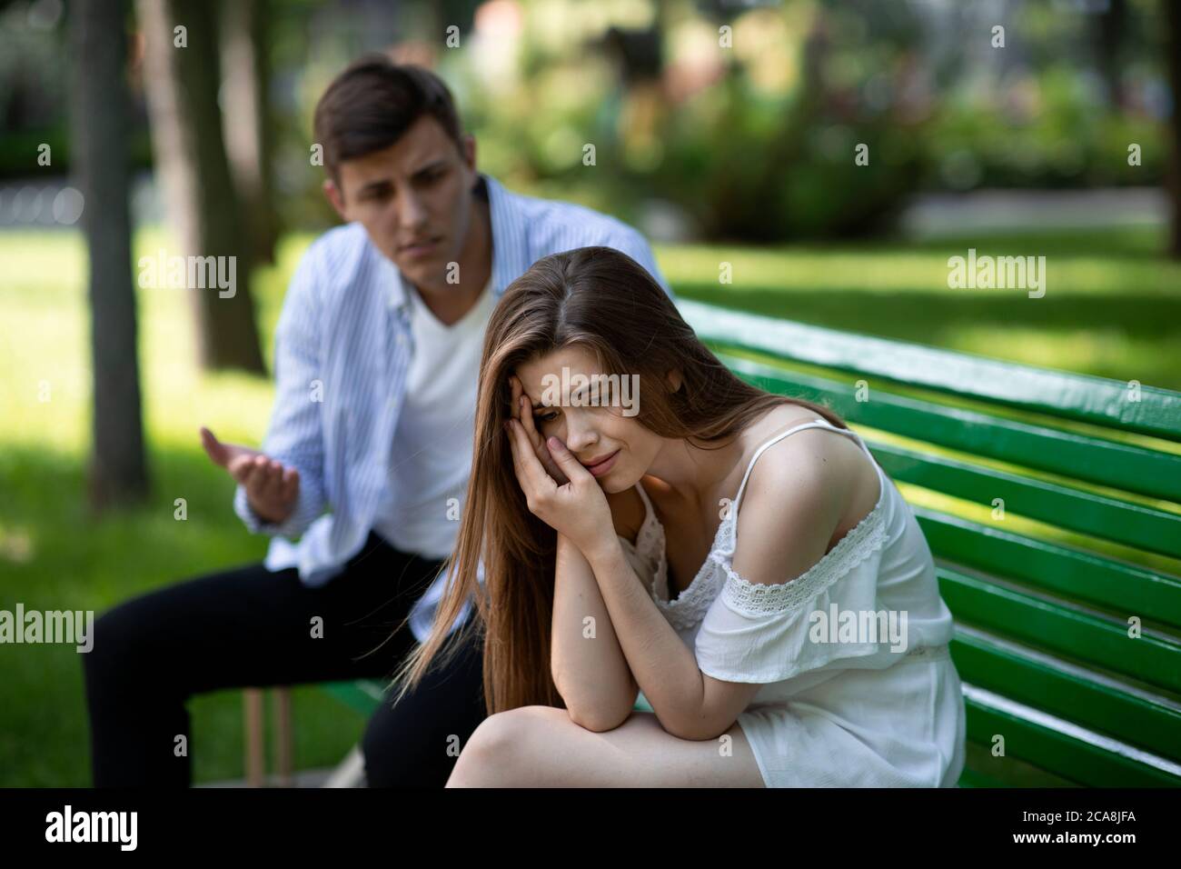 Domestic violence. Angry man and his desperate battered wife on bench ...