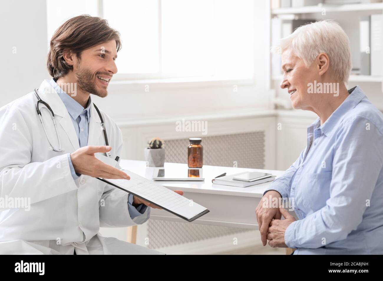 Cheerful doctor explaining treatment plan to senior female patient ...