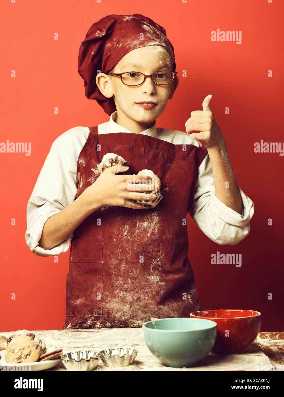 young boy cute cook chef in uniform and hat on stained face flour with ...