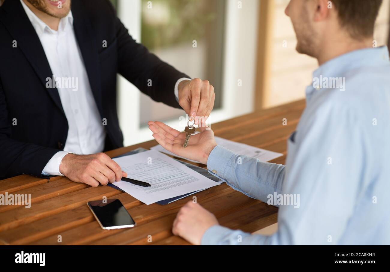 Closeup view of real estate agent giving house keys to male client at ...