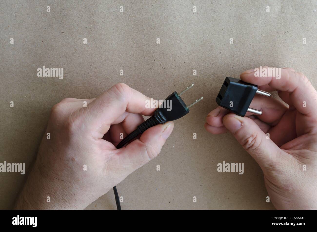 An adult Caucasian male is holding power plug adapter. Black AC and DC ...