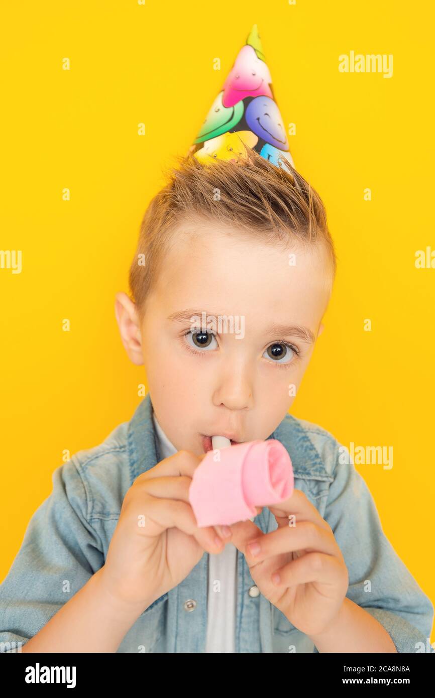 Funny kid in party hats blowing party horns at camera Stock Photo - Alamy