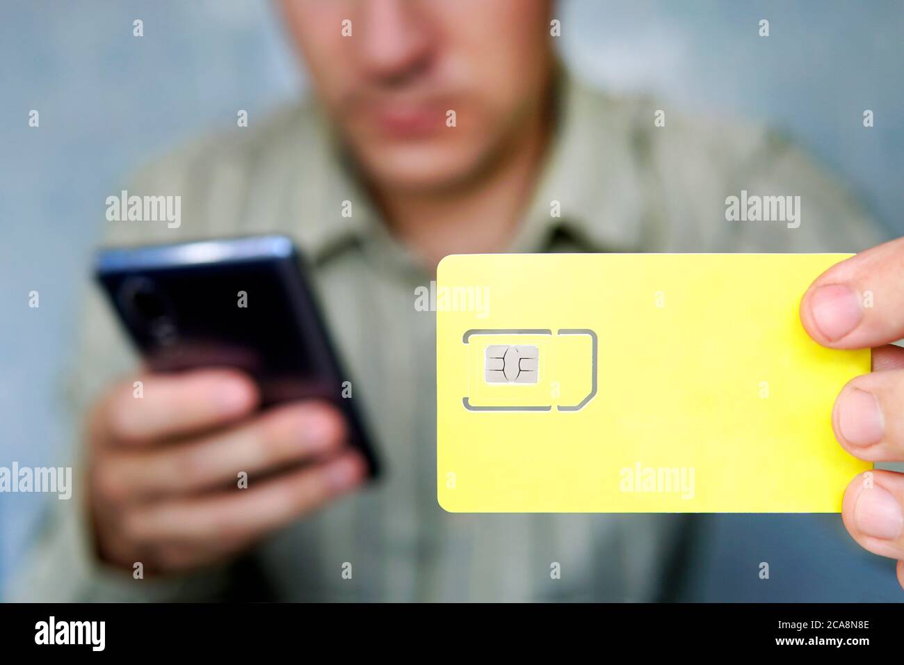 man holds a yellow SIM card and a mobile phone in his hand. free space ...
