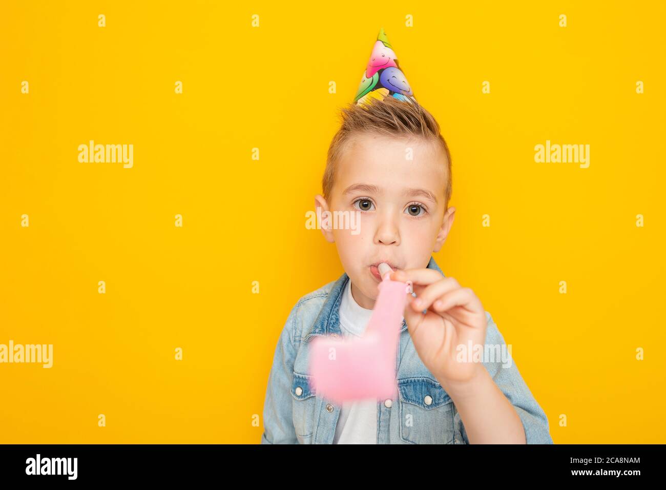 Little kid in party hats blowing party horns at camera Stock Photo - Alamy