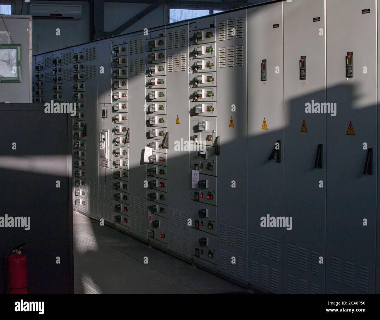 Grey electric cabinet with switchers and lamp indicators half in shadow ...