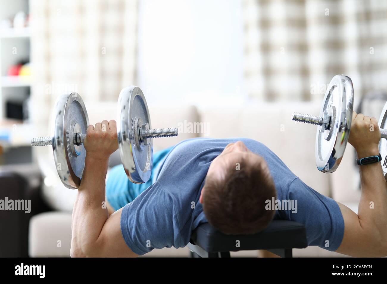 Muscular man lifting heavy dumbbells at home Stock Photo - Alamy