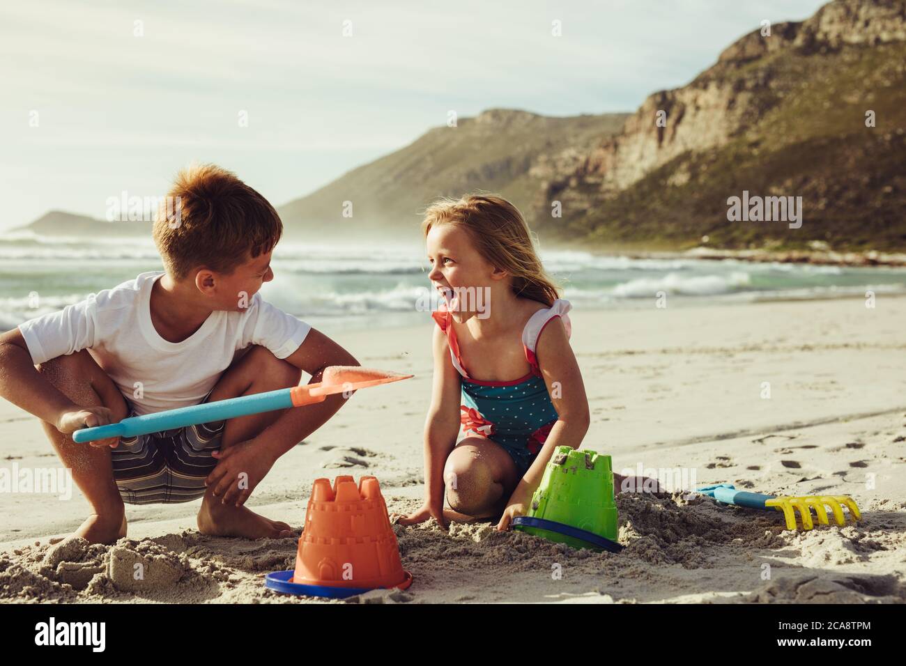 Two children playing with sand on the beach. Small boy and girl ...