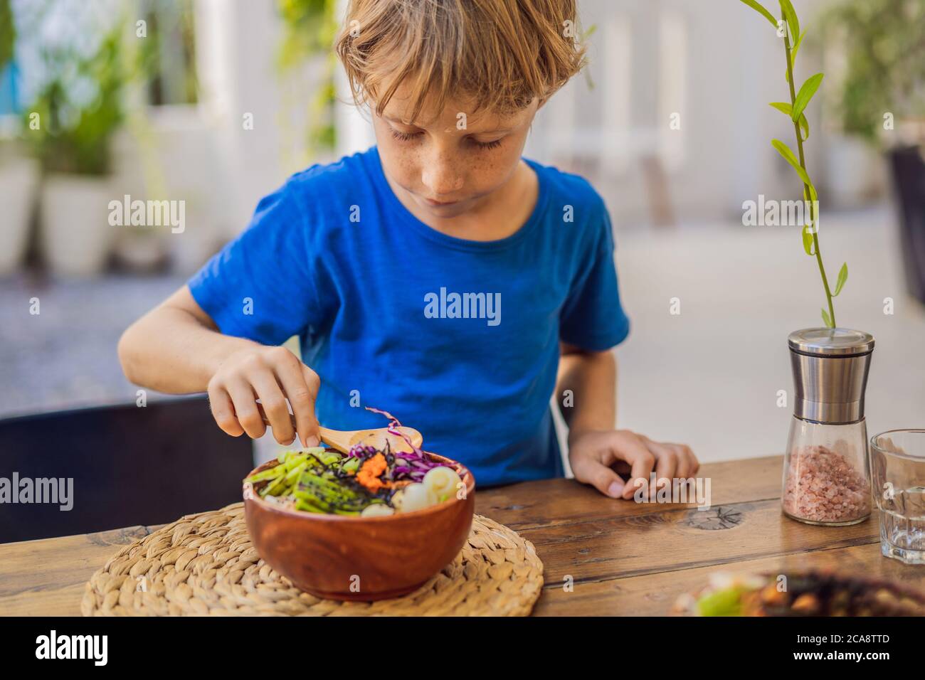 Boy eating Poke bowl with shrimp, corn, avocado, ginger and mushrooms ...