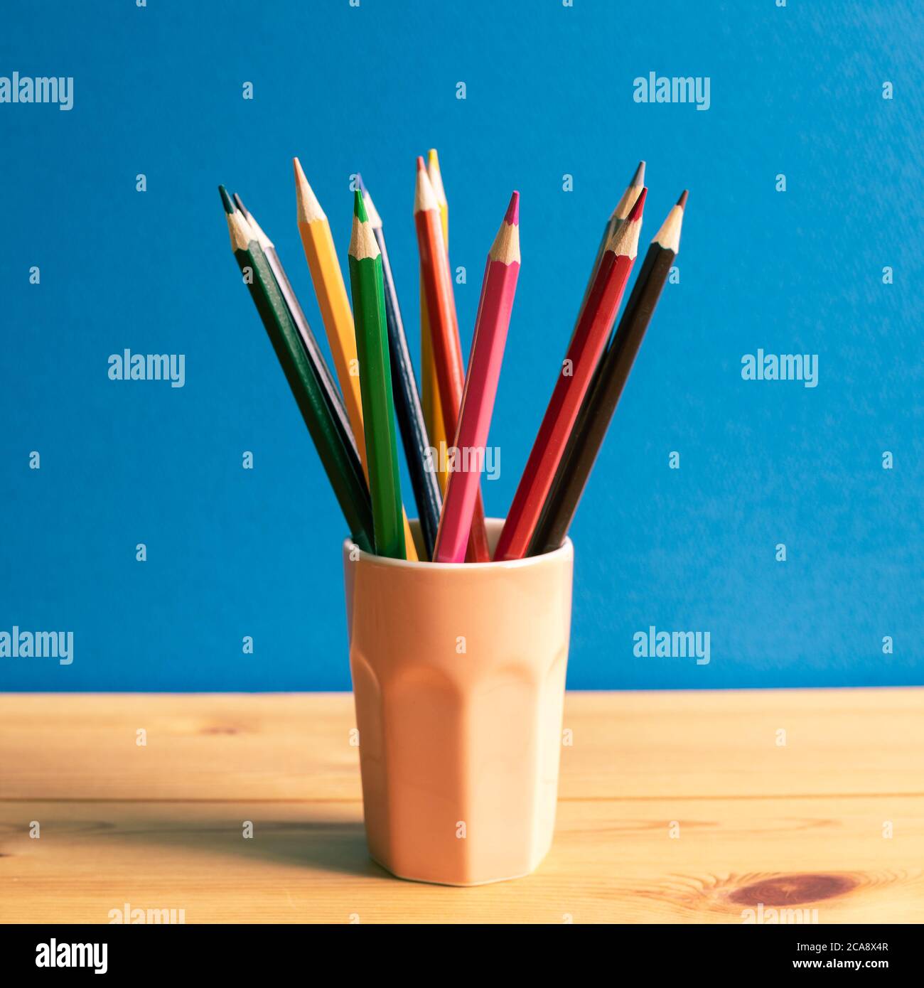Color pencils in holder on wooden desk with blue background Stock Photo ...