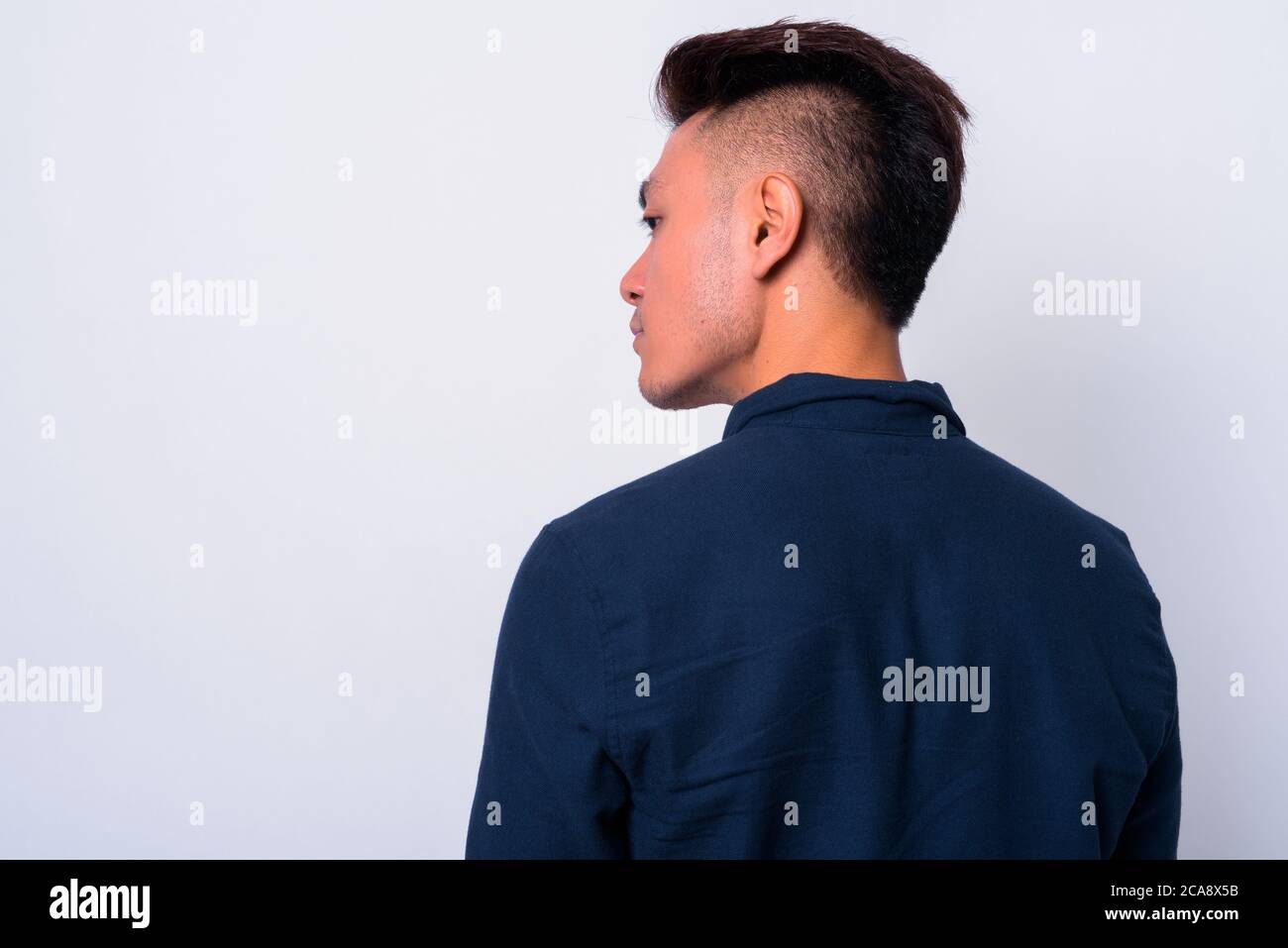 Closeup rear view of young Asian businessman looking over shoulder ...