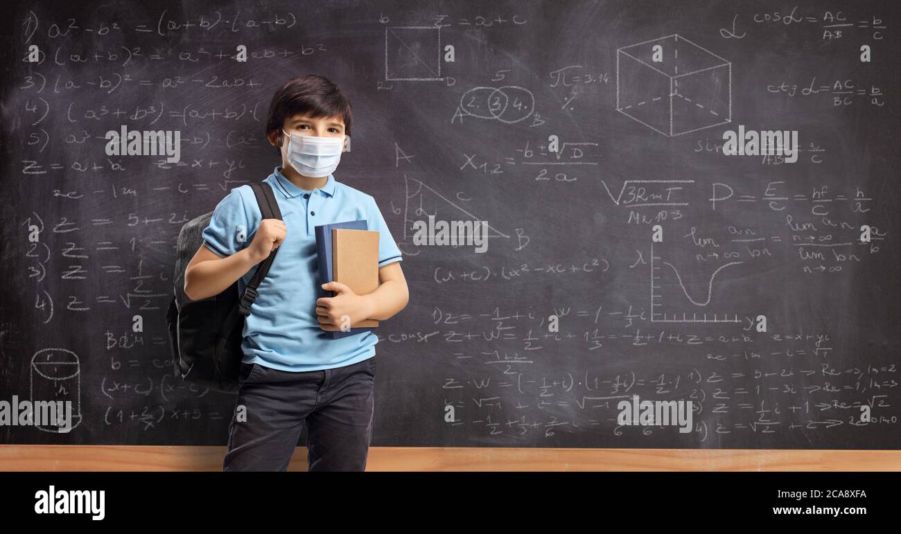 Schoolboy wearing a protective face mask and standing in front of a ...