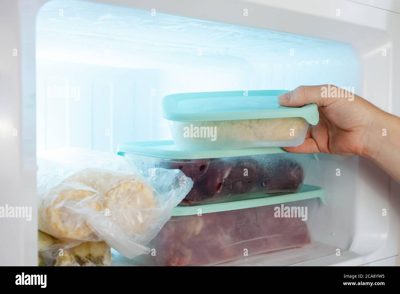 A man pulls frozen vegetables out of the freezer. A man takes corn from ...