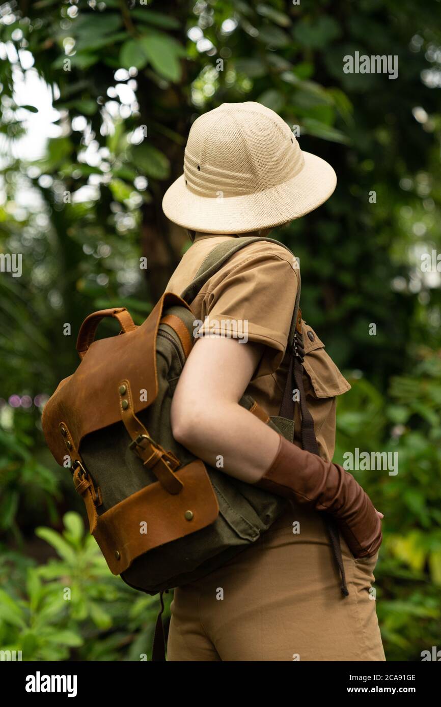 Woman botanist dressed in safari style in greenhouse, back view ...