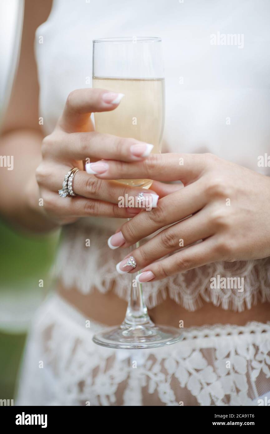 wedding and engagment ring on hand with champagne. woman's hand with ...