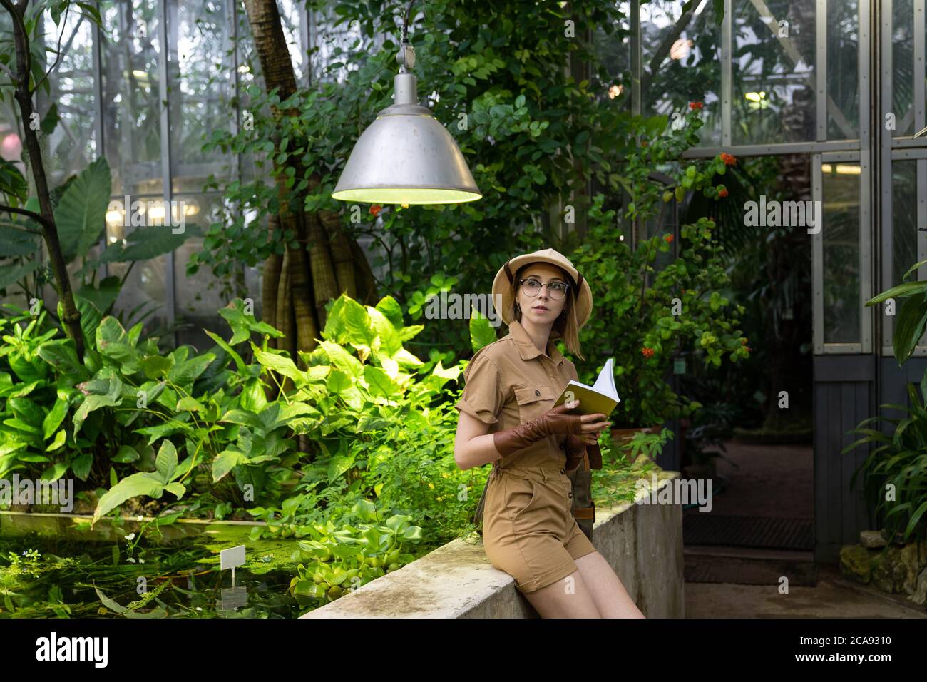 Woman botanist dressed in safari style in greenhouse. Naturalist ...