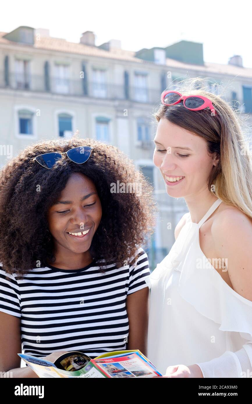 Two friends, one African and one Caucasian, sharing a map together ...