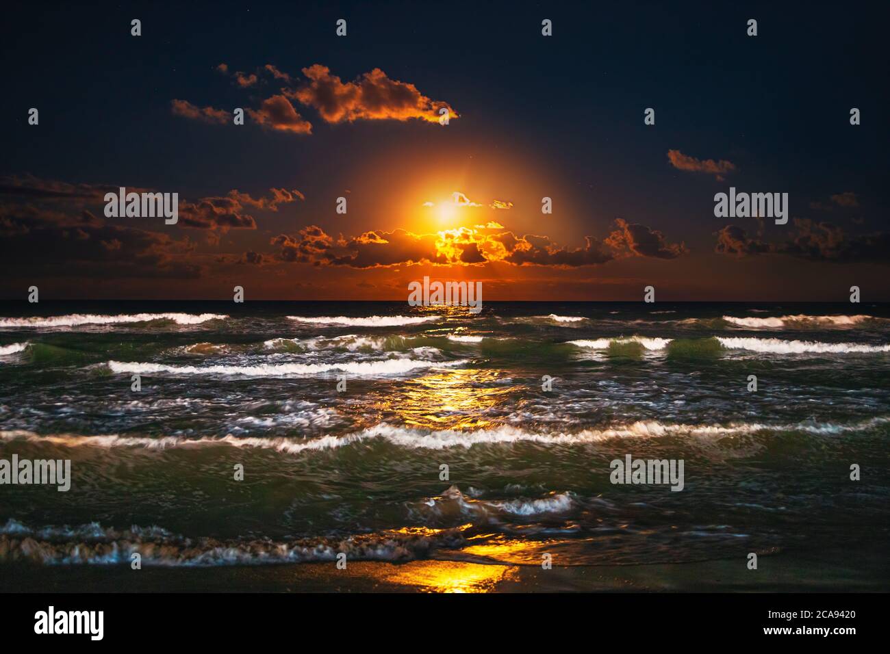 Full moon rising over sea waves. Dramatic sunset over beach Stock Photo ...