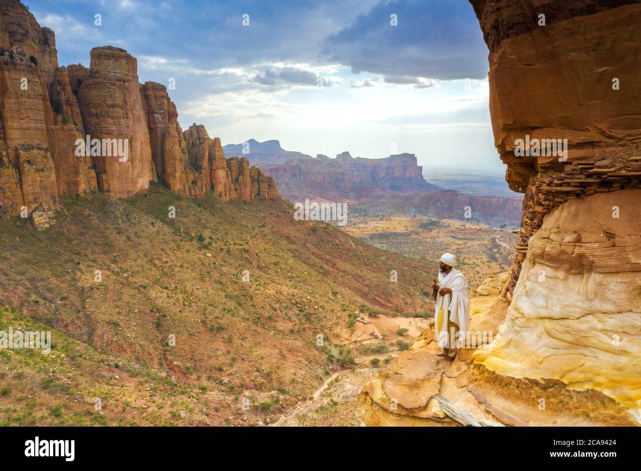 Orthodox priest admiring Gheralta Mountains,the entrance of Abuna Yemata Guh church, Tigray ...