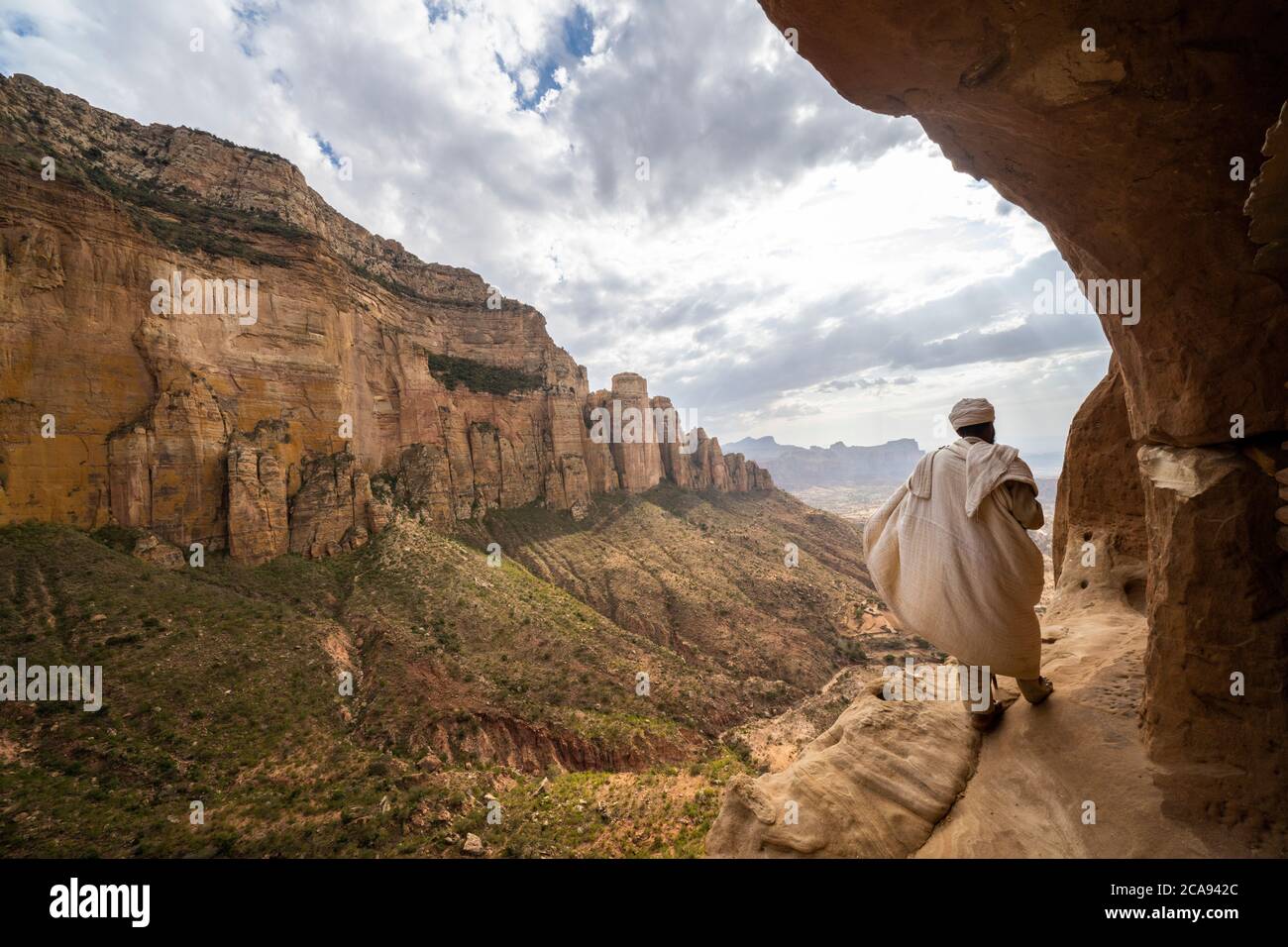 Rear view of priest walking on access trail to the rock-hewn Abuna ...