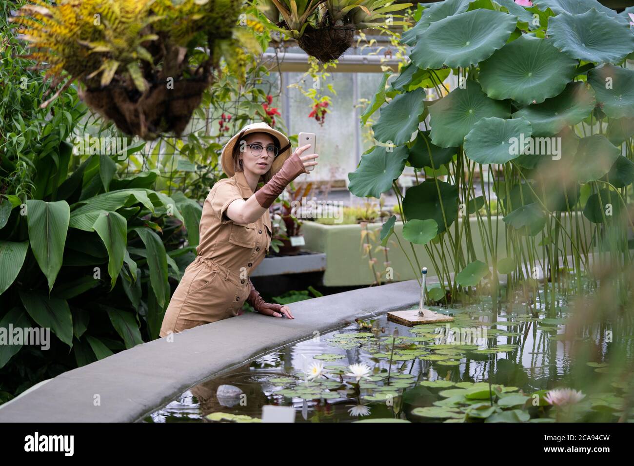 Woman botanist dressed in safari style in greenhouse. Naturalist in ...