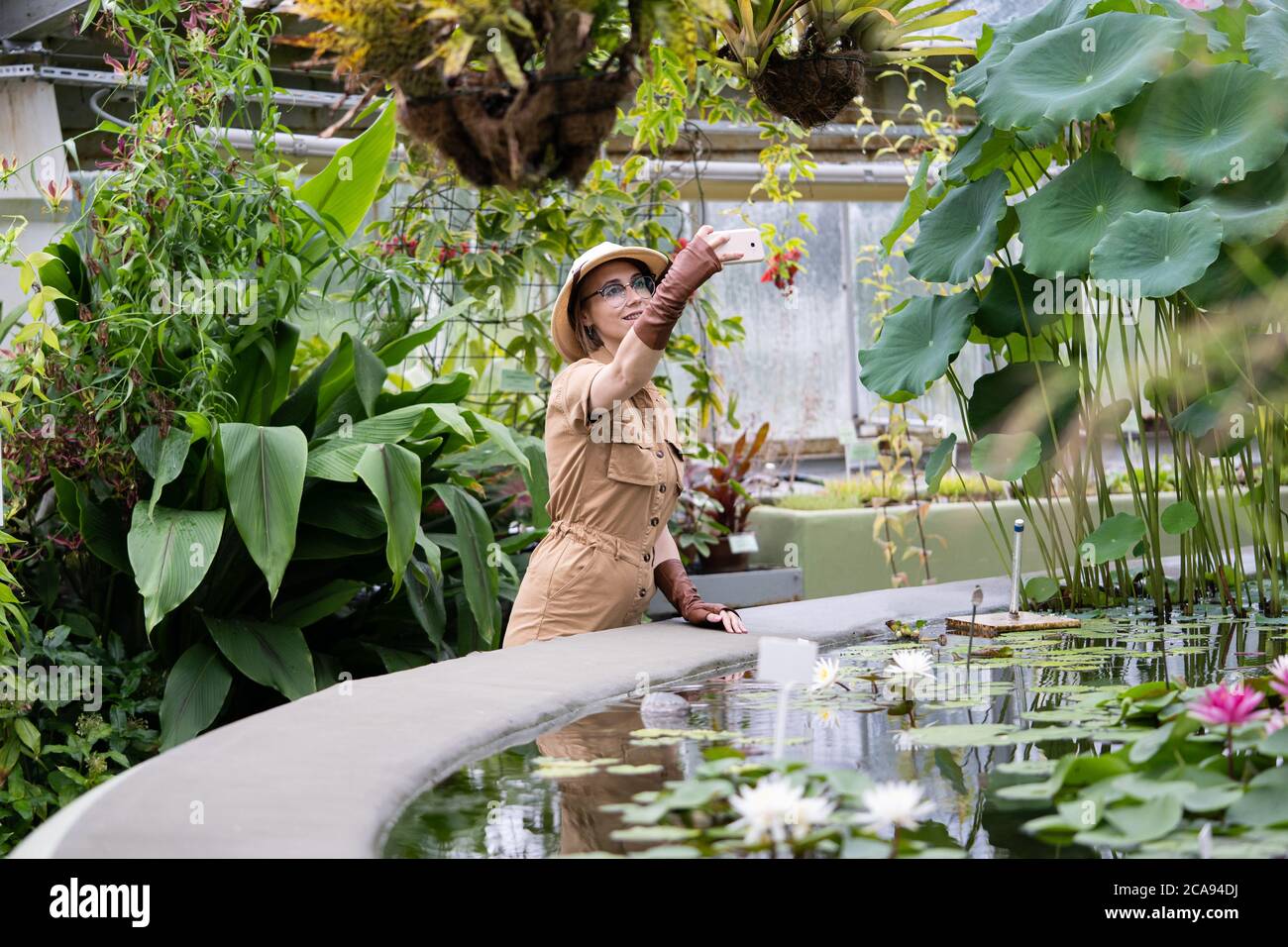 Woman botanist dressed in safari style in greenhouse. Naturalist in ...
