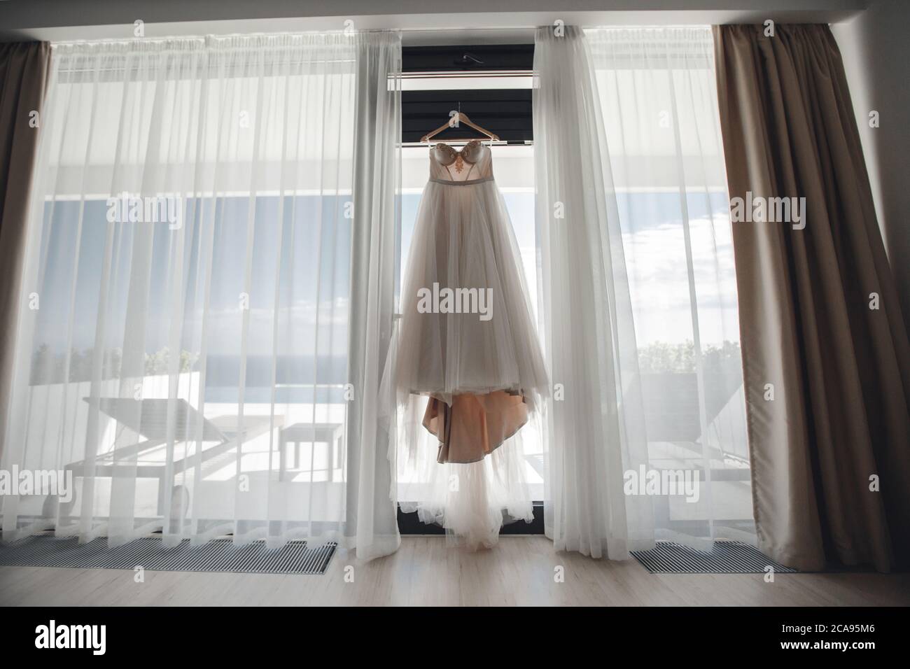 bride's morning. wedding dress at the window indoors Stock Photo - Alamy