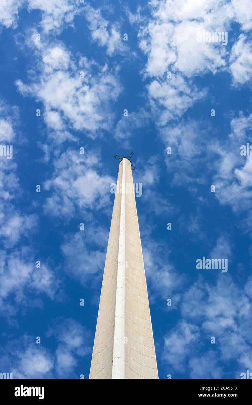 the concrete spire of the antenna rises up against the blue sky and ...