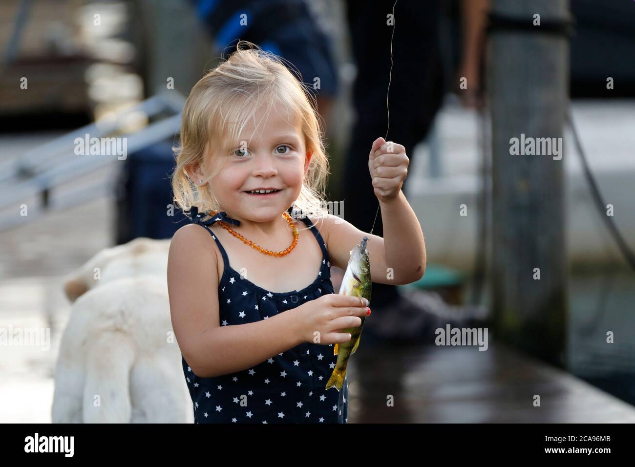 A girl child holding a small fish that she caught Stock Photo - Alamy