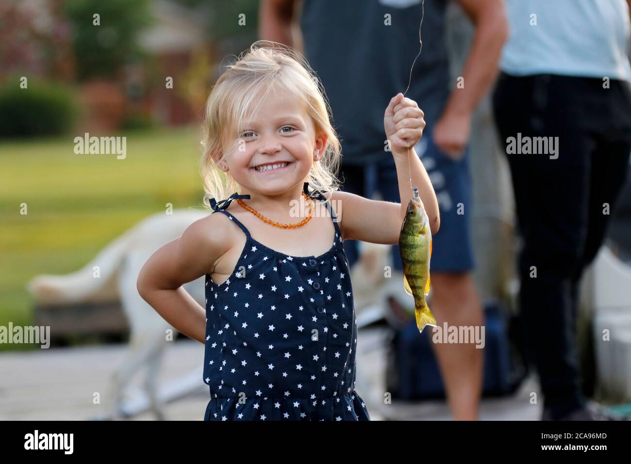 A smiling young girl holding a small fish Stock Photo - Alamy