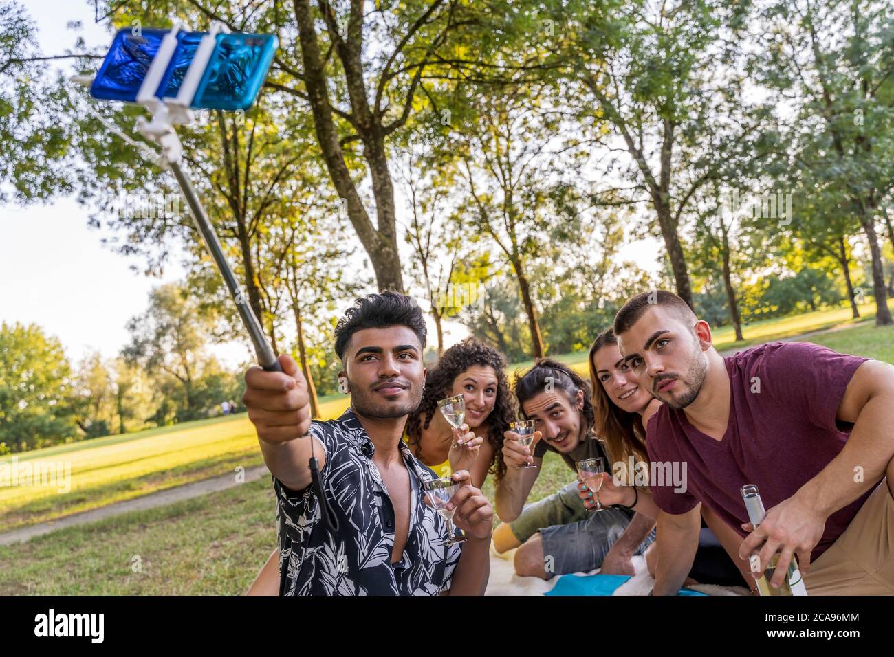 multiethnic group of millennial friends take a selfie while celebrating ...