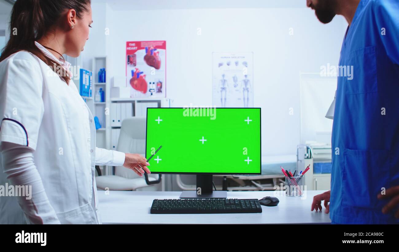 Doctor explaining on computer with green screen in hospital cabinet to ...